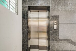 Um elevador com interior metálico e painel de controle à direita.