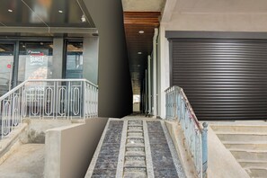 Escada que leva a uma área comercial com uma porta de persiana fechada e um corrimão de metal.