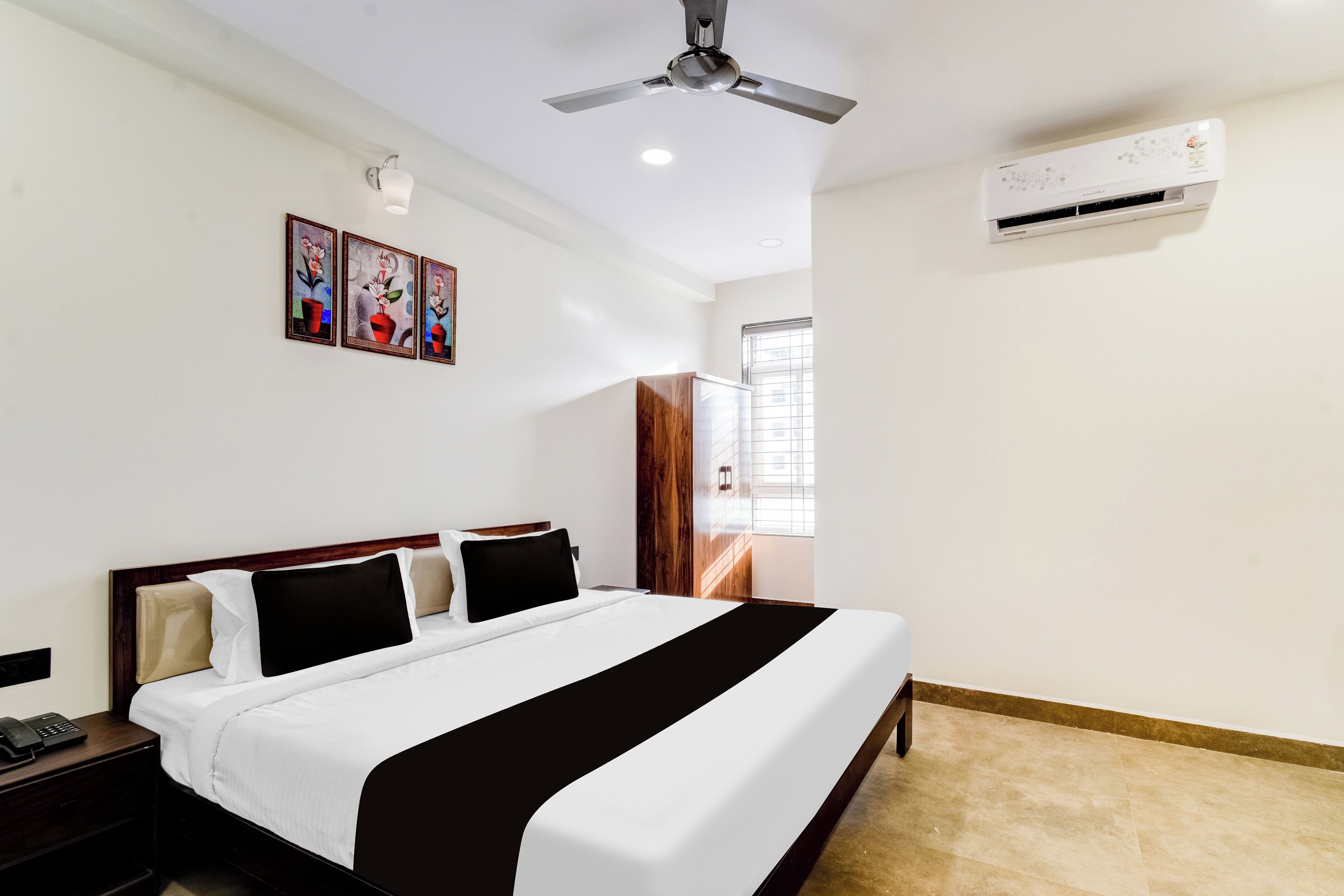 Quarto de hotel com cama, mesa de cabeceira e ventoinha no teto.