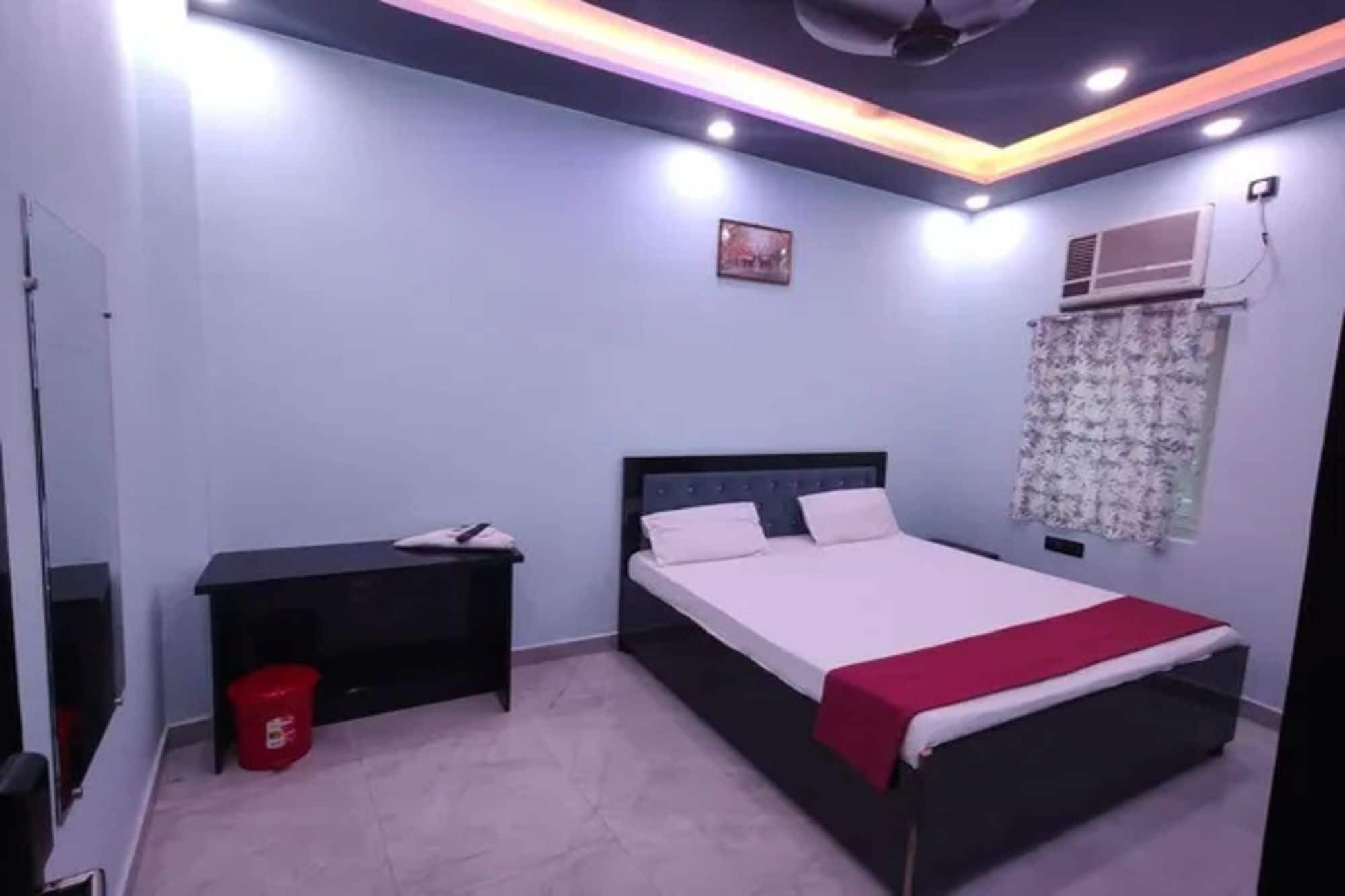 Quarto com cama, escrivaninha, lixeira vermelha e ar-condicionado fixado na parede.