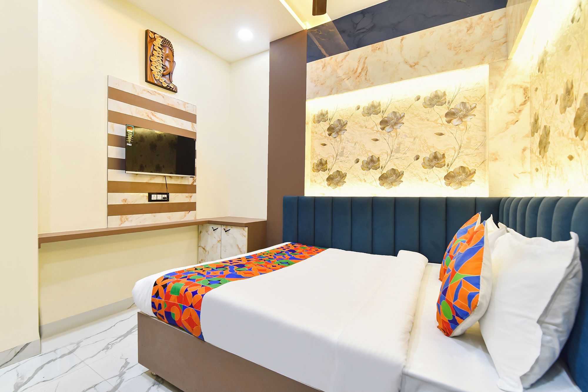 Quarto de hotel com uma cama, televisão fixada na parede e um painel decorativo.