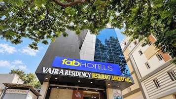 Fachada de hotel com placa indicando 'fahotels' e 'Vajra Residency Restaurant | Salão de Festas'.
