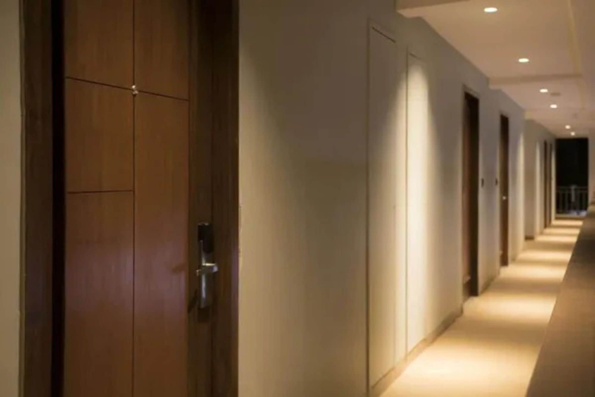 Corredor de hotel com portas de madeira e piso coberto por carpete.