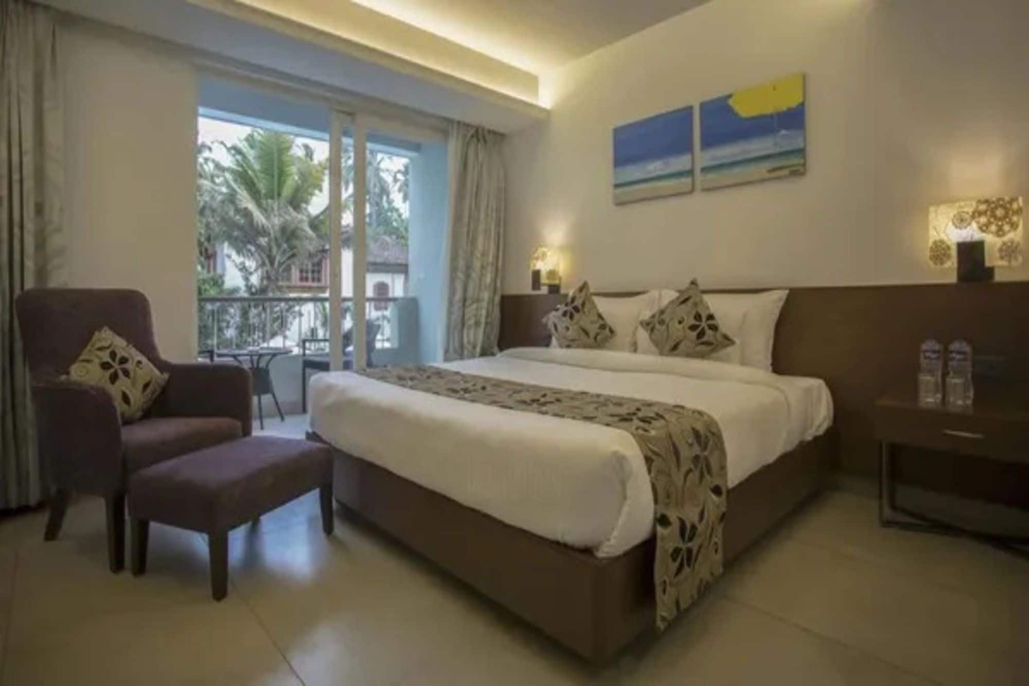 Quarto de hotel com cama, cadeira, mesa e vista para o exterior.