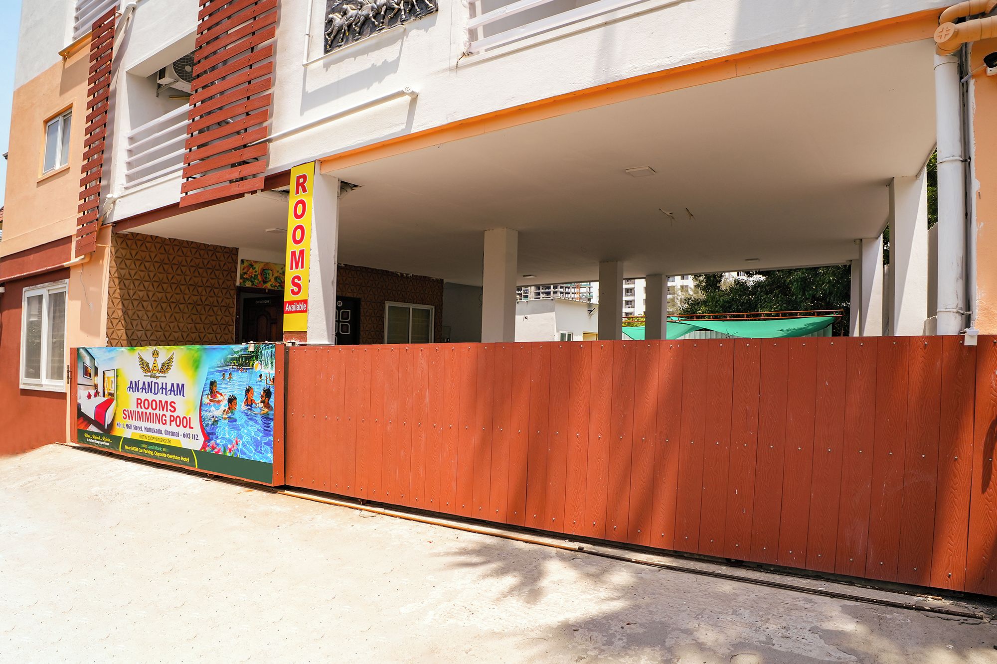 Hotel com piscina, cerca vermelha e placa anunciando quartos.