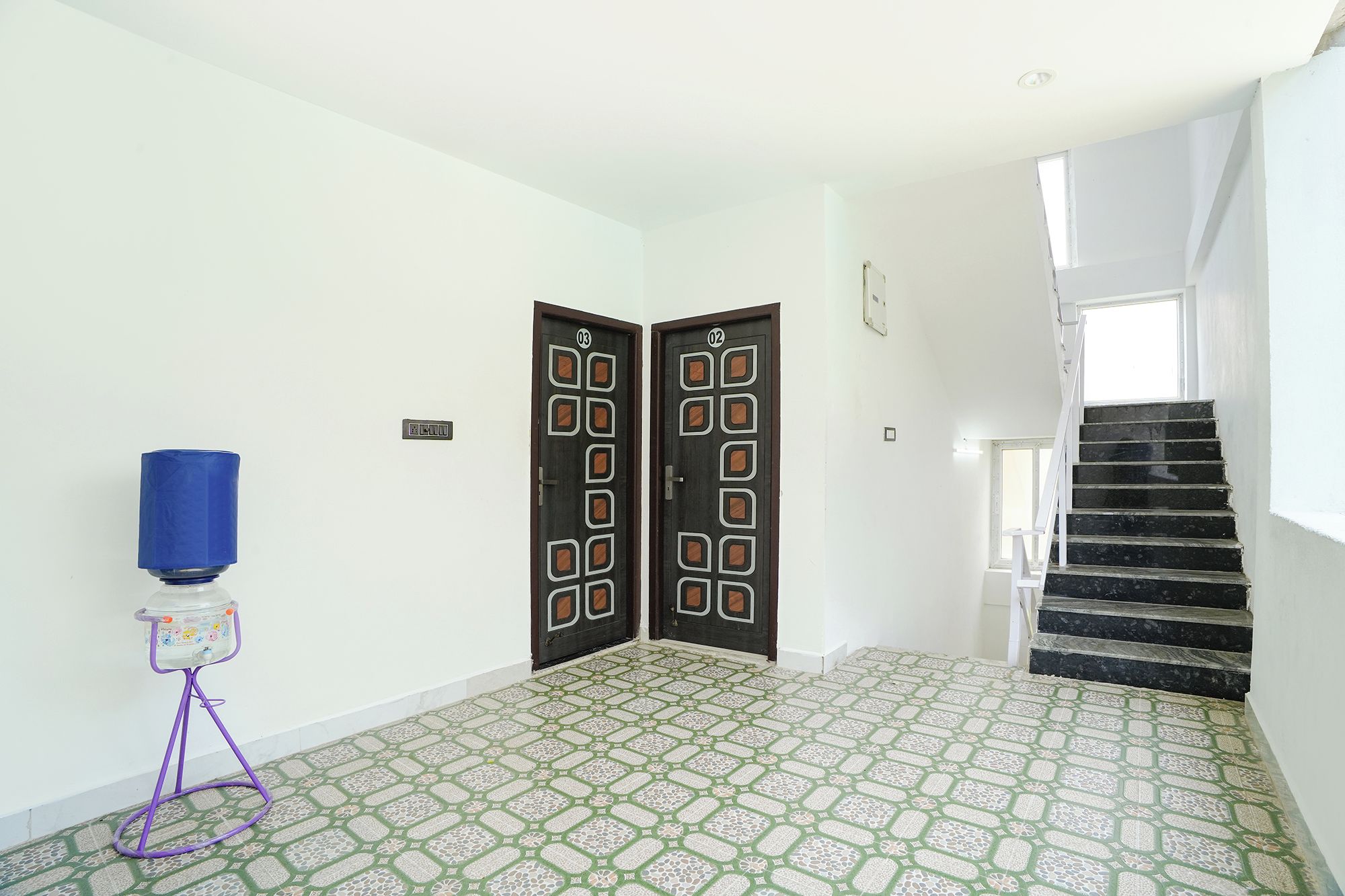 Quarto com duas portas, escada e uma pequena mesa com um objeto azul.
