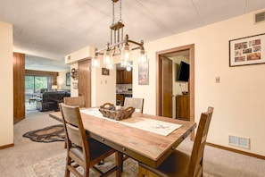 Uma sala de jantar com mesa de madeira, cadeiras e lustre.