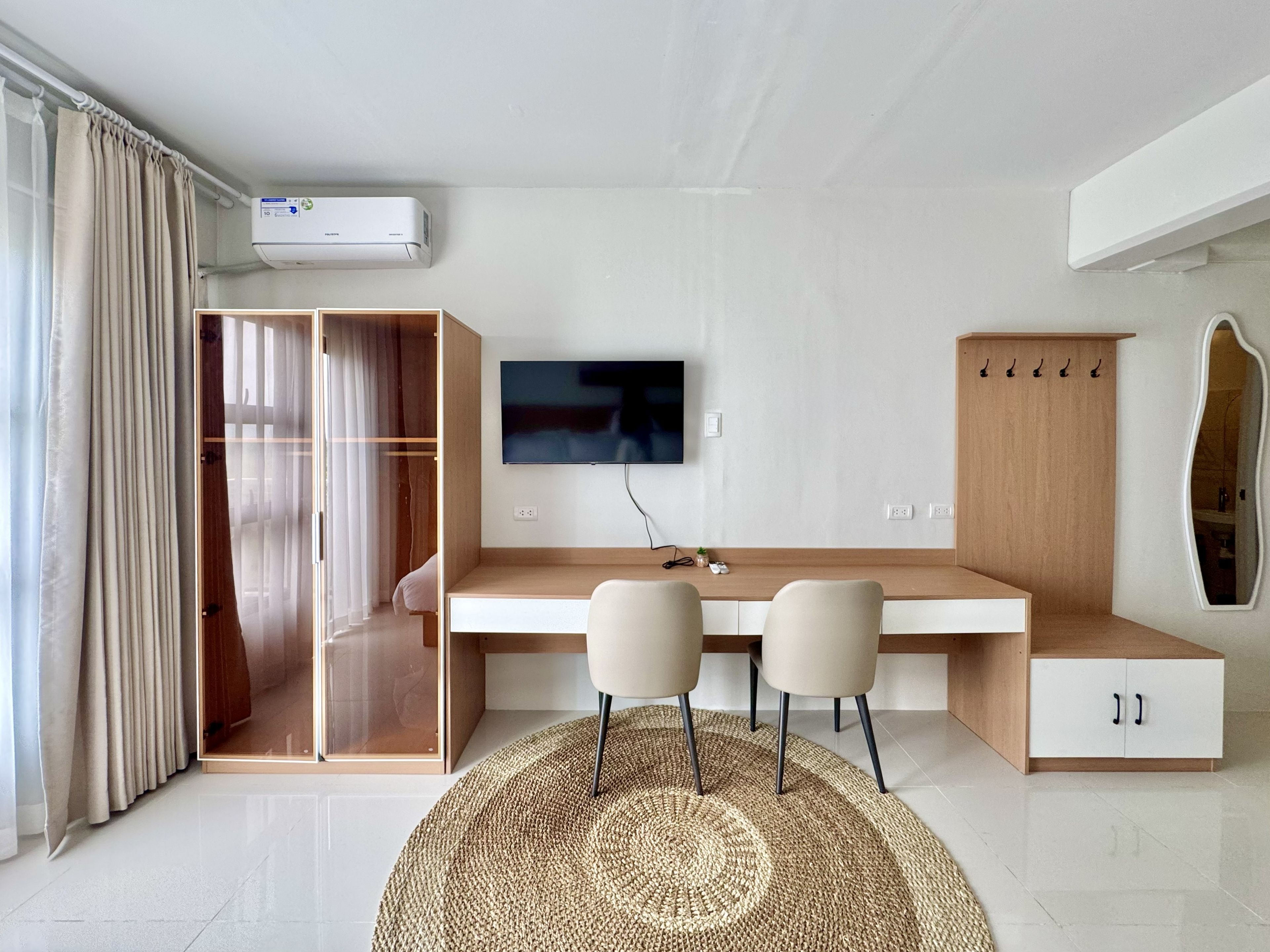 Quarto moderno com escrivaninha, duas cadeiras, televisão, guarda-roupa e espelho.