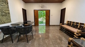 Quarto com mesa de jantar e cadeiras, um sofá, porta de madeira e parede com escultura em relevo.