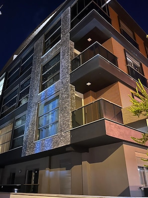 Um edifício moderno de vários andares, com varandas e grandes janelas.