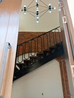 Escadaria com guarda-corpo de metal e luminária pendente.
