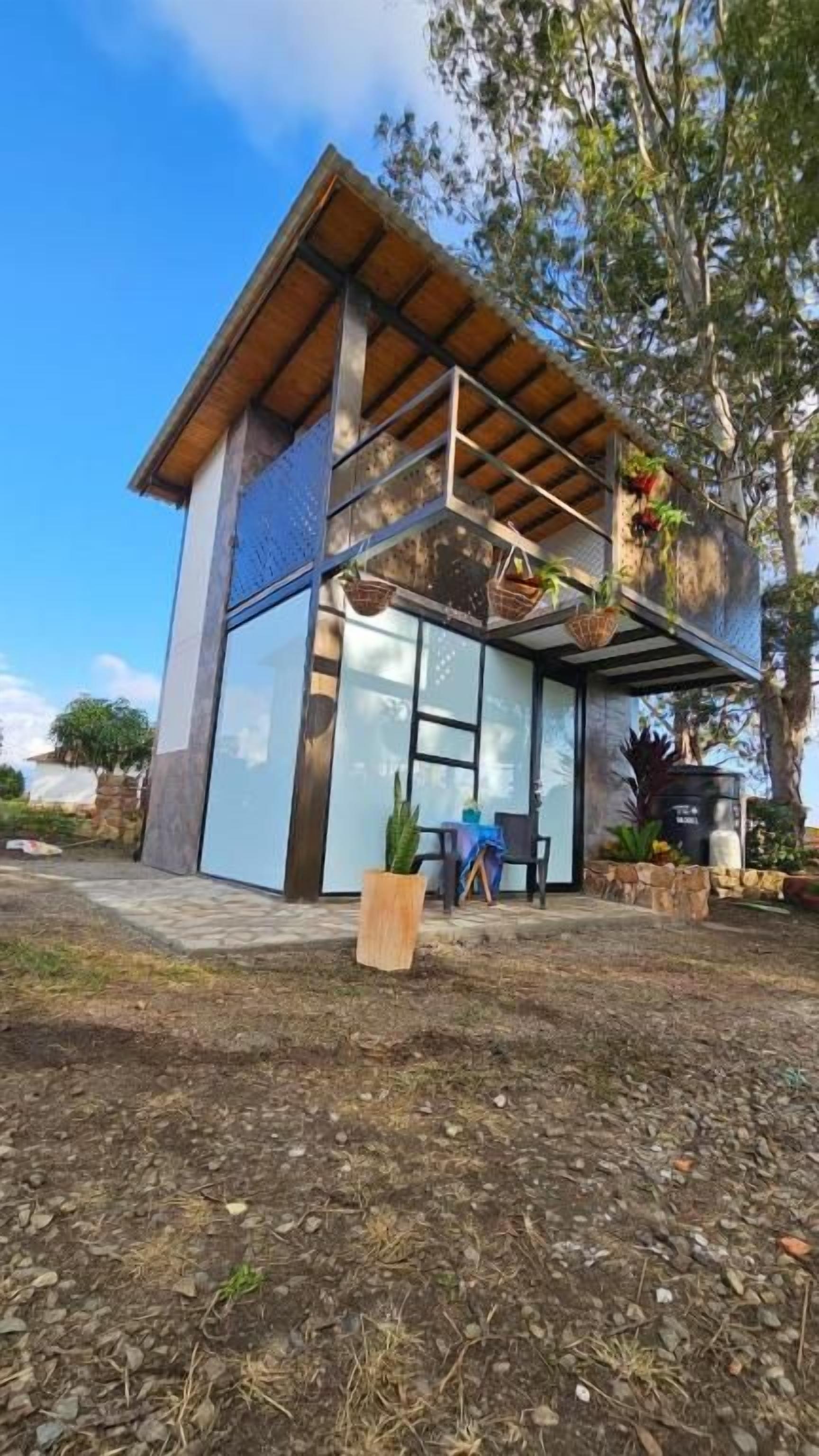 Uma casa moderna com fachada de vidro, deck de madeira e plantas em vasos.