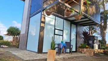 Uma casa moderna com fachada de vidro, deck de madeira e plantas em vasos.
