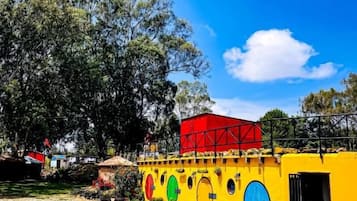 Um edifício com fachada amarela, telhado vermelho e porta preta.