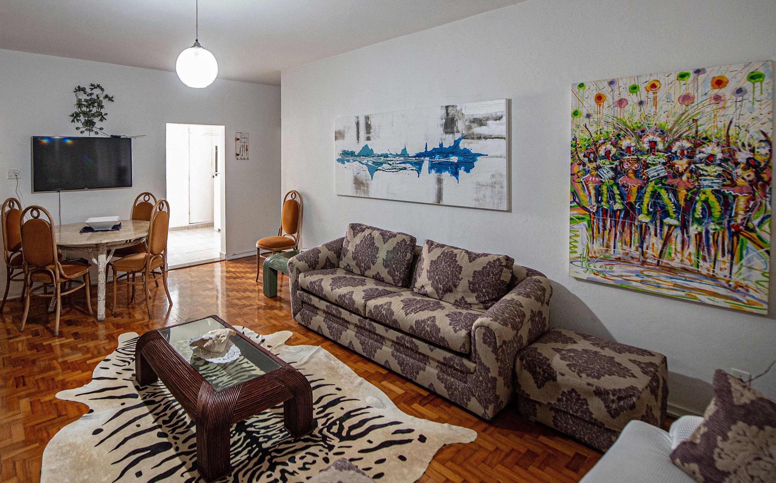 Uma sala de estar com um sofá, uma mesa de centro e um quadro na parede.