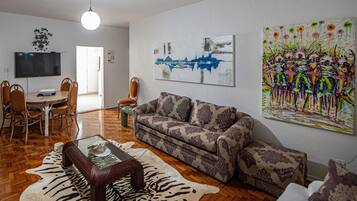 Uma sala de estar com um sofá, uma mesa de centro e um quadro na parede.