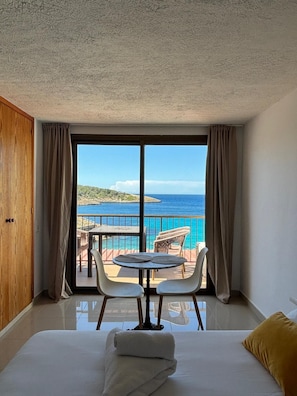 Quarto de hotel com varanda, cama e vista para o mar.