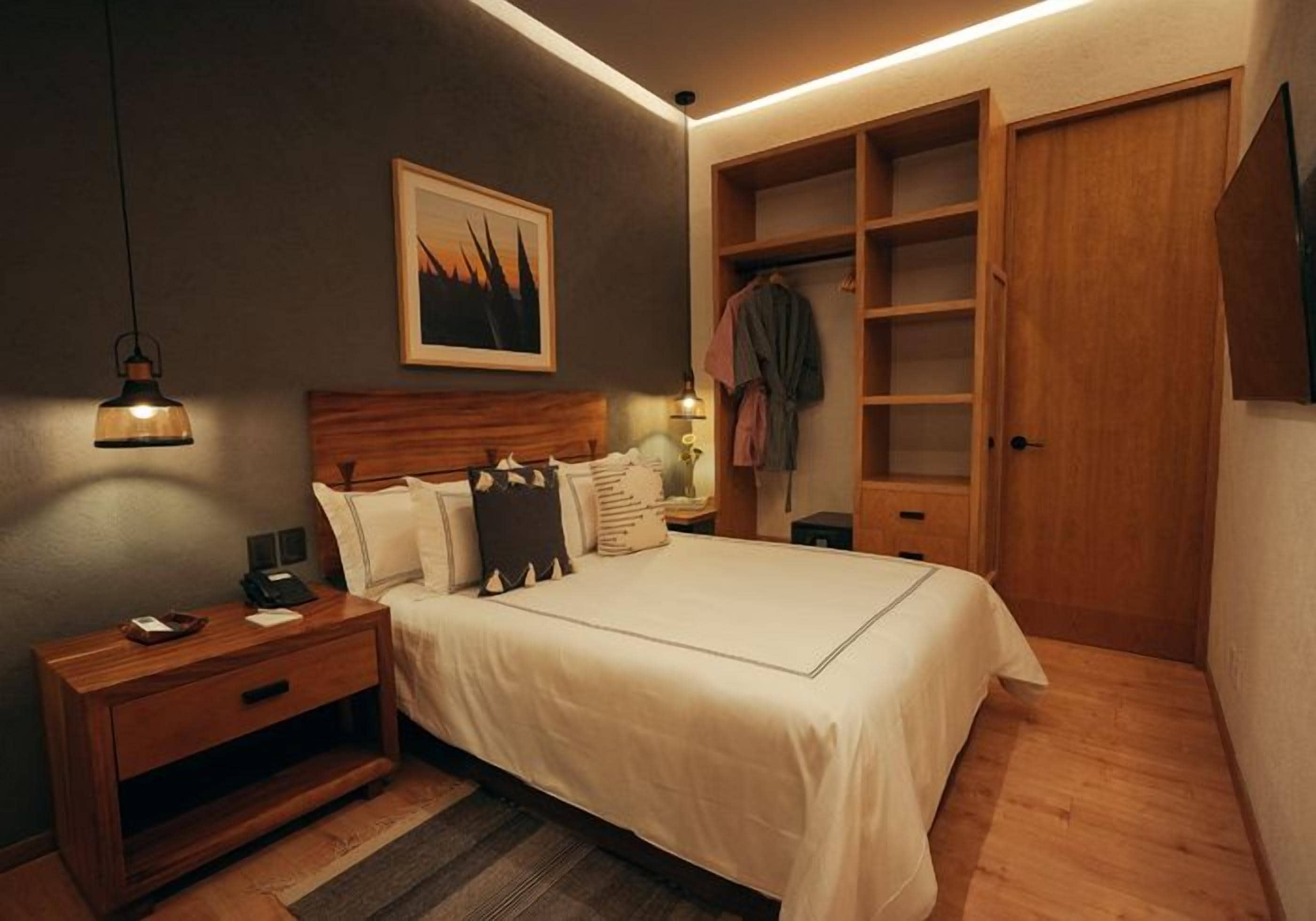 Quarto com cama, mesa de cabeceira, luminária e guarda-roupa.