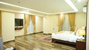 Quarto de hotel com cama, mesa de cabeceira, abajur e televisão.