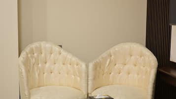 Quarto com duas poltronas estofadas viradas uma para a outra, uma mesa redonda pequena e um tapete estampado no chão.