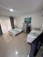 Quarto de hotel com duas camas, um refrigerador, uma televisão e um quadro na parede.