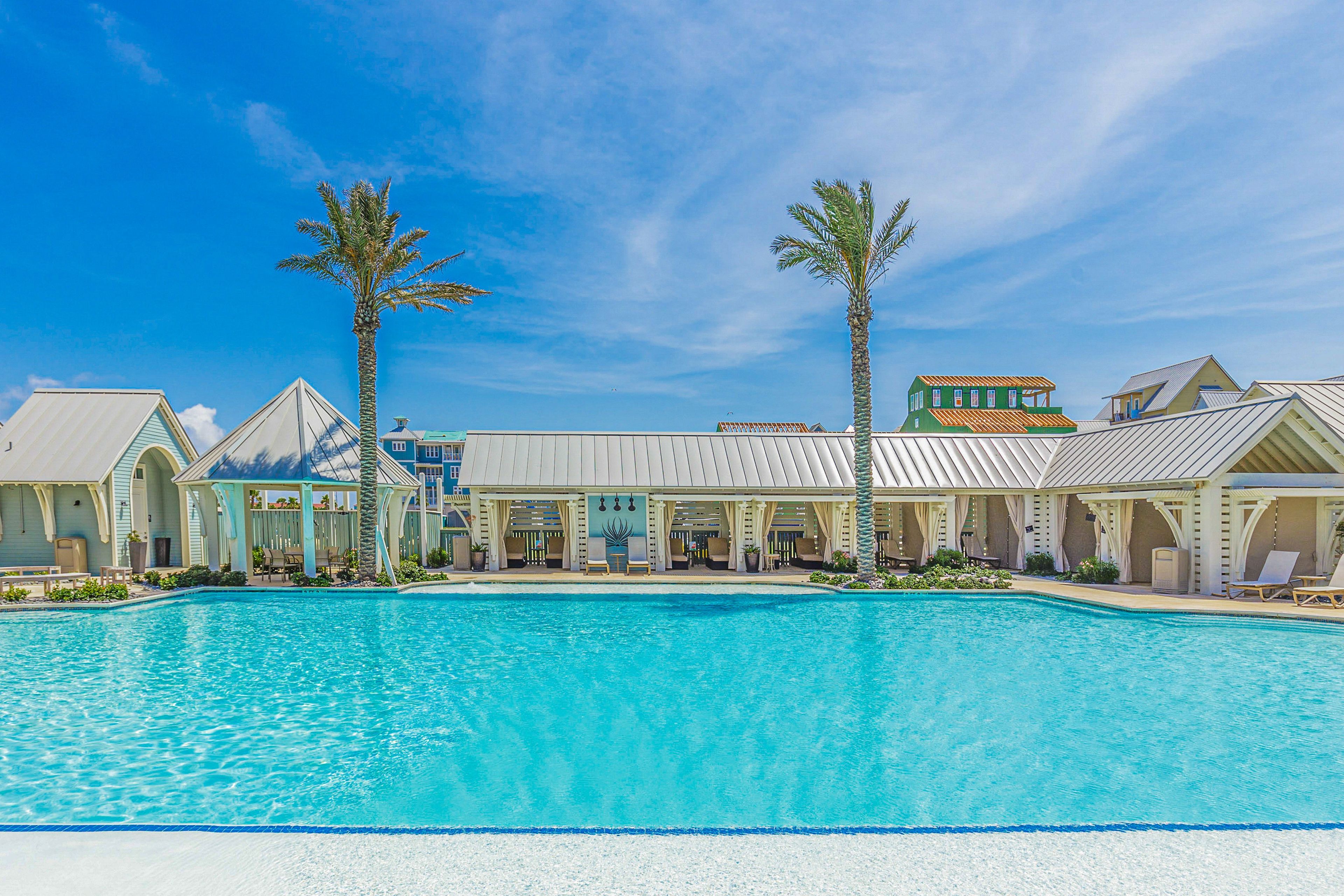 Um resort com piscina, palmeiras e um céu azul límpido.