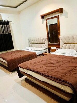 Quarto de hotel com duas camas, um espelho grande e uma janela com cortinas.