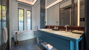Uma casa de banho moderna com banheira, duas pias e um espelho grande.