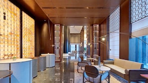 Um lobby de hotel moderno com balcão de recepção, área de estar e elementos decorativos.