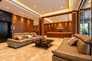 Um lobby moderno com balcão de recepção, sofás e uma mesa de centro de mármore.