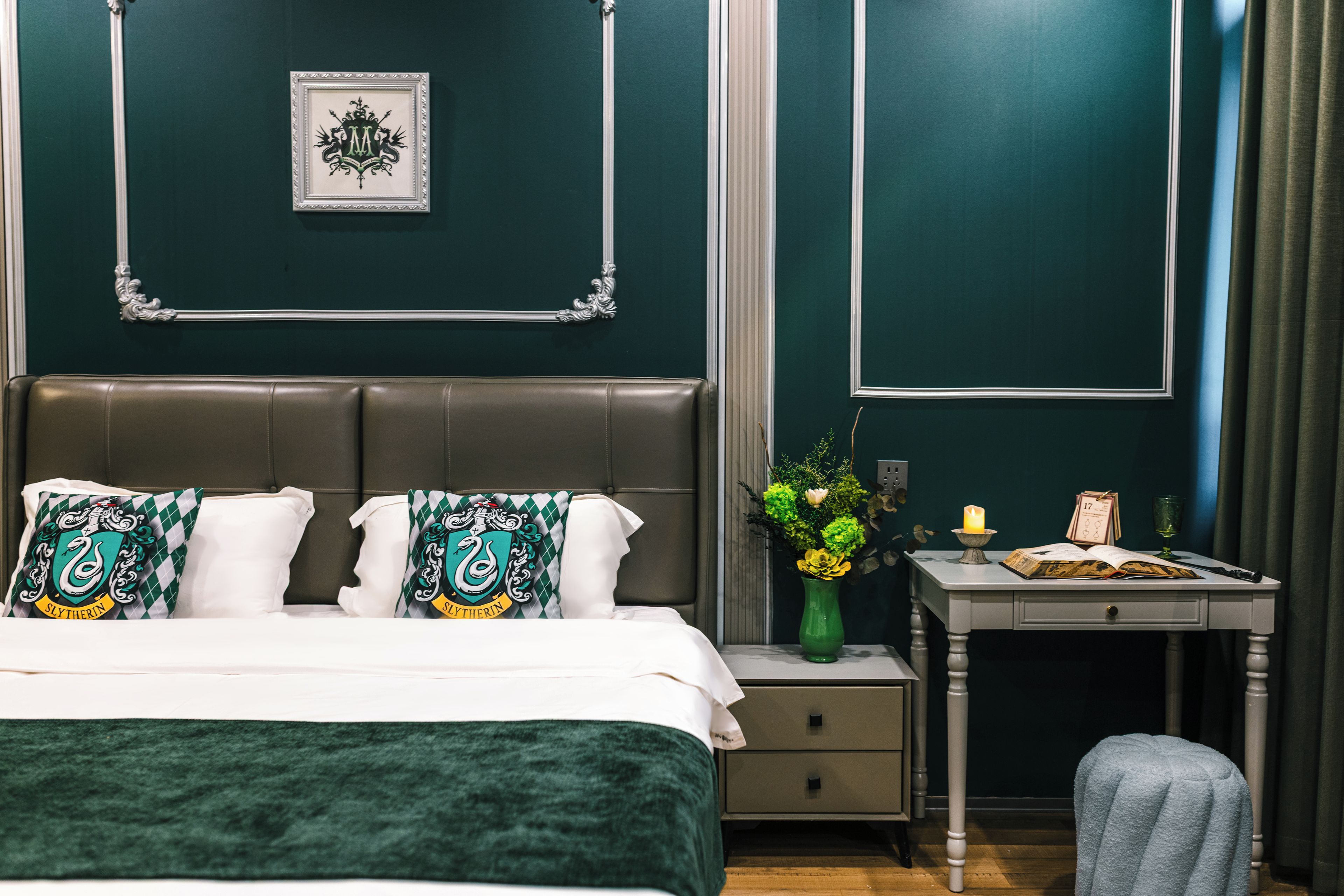 Quarto bem arrumado com cama, almofadas, mesa de cabeceira, escrivaninha e uma cadeira.
