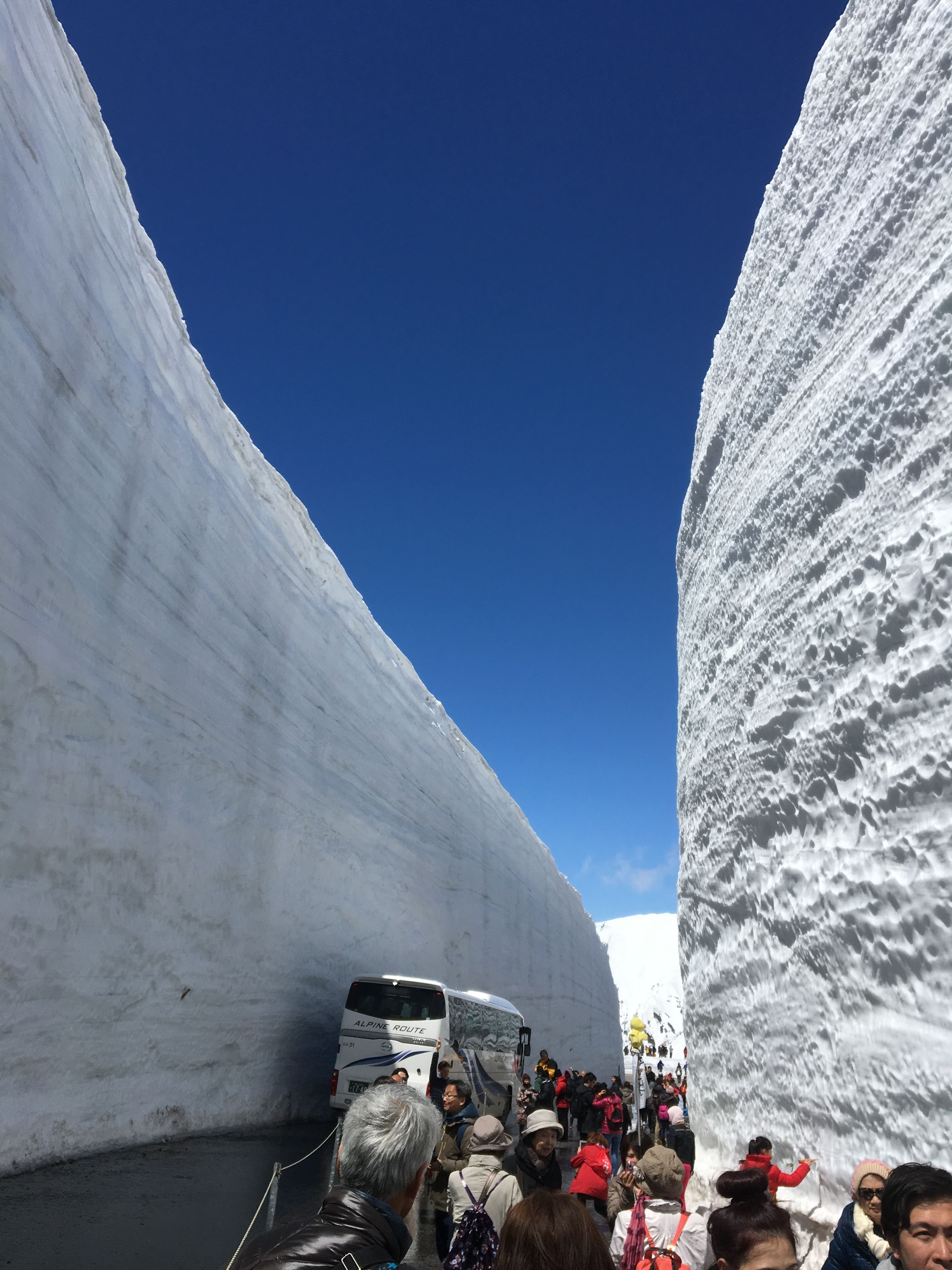 Um grupo de pessoas em uma passagem estreita, flanqueada por paredes altas cobertas de neve.