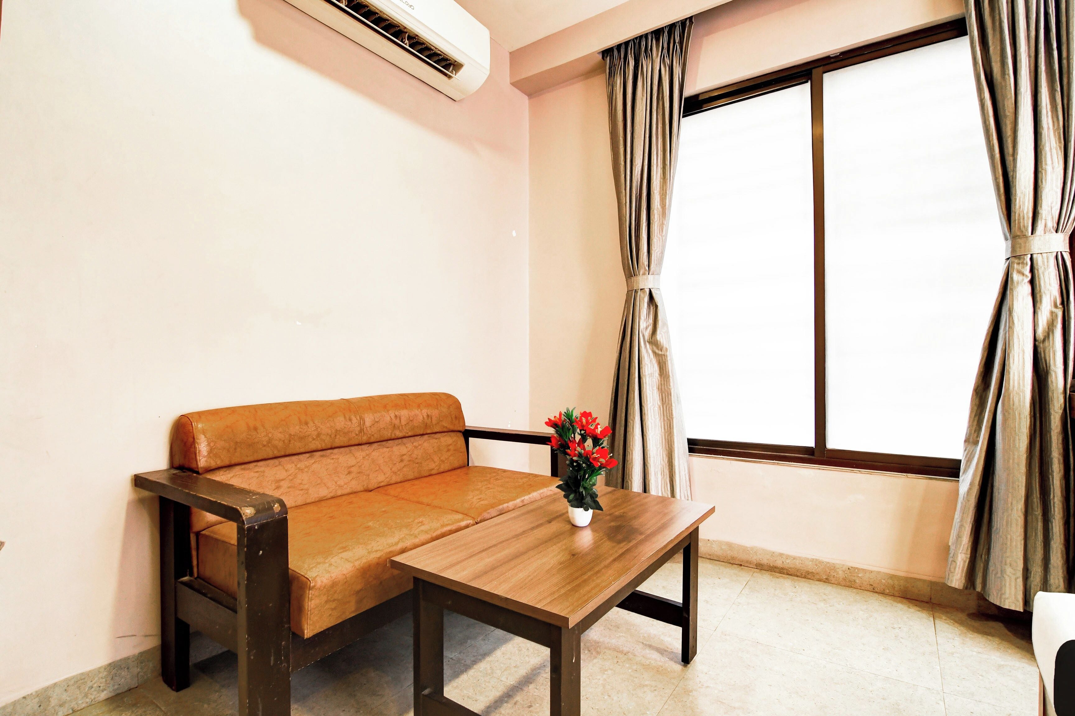 Quarto com sofá, mesa e janela com cortinas.