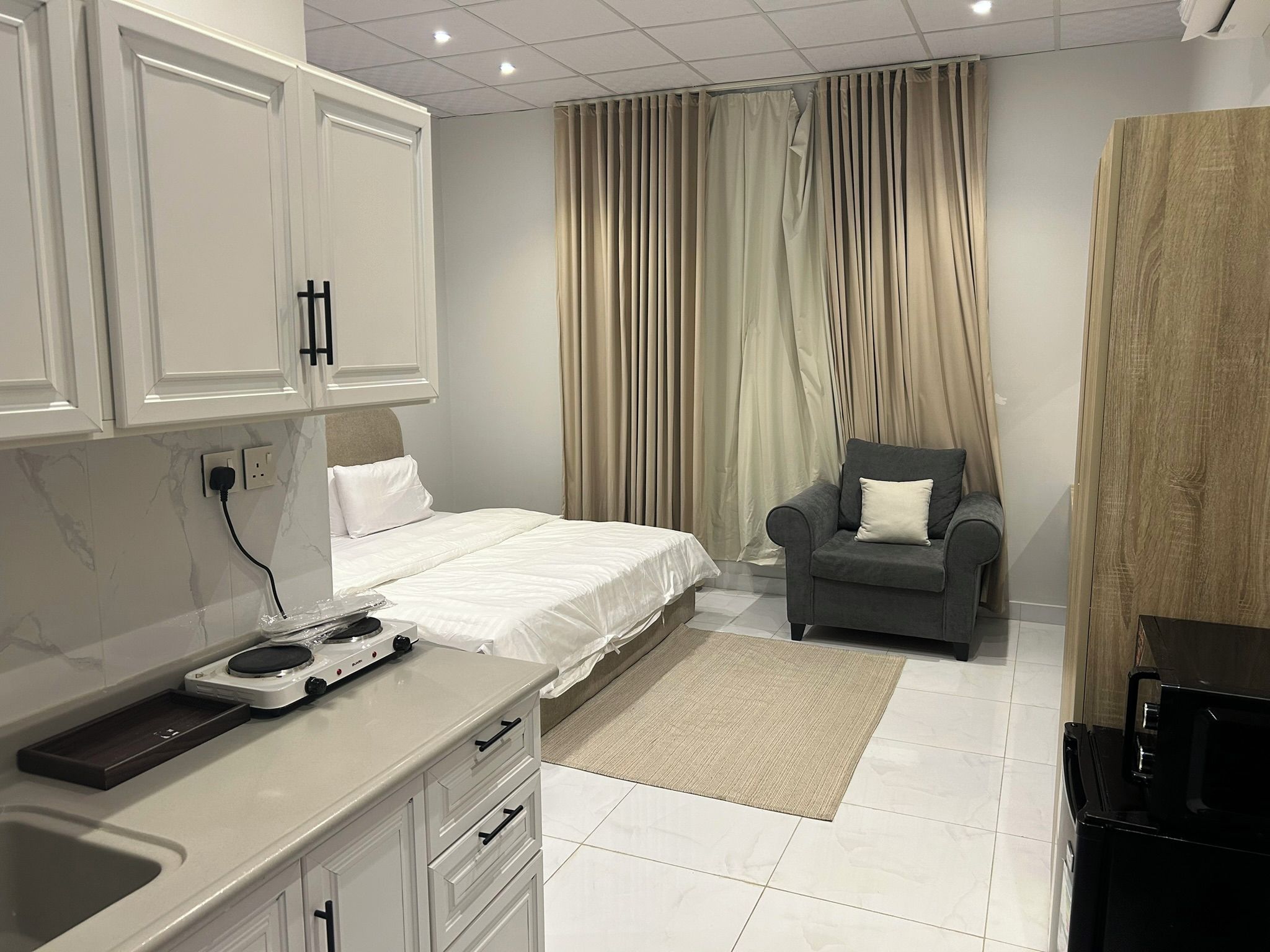 Quarto moderno com cama, cadeira, escrivaninha com fogão e guarda-roupa.
