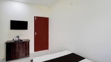 Quarto com cama, penteadeira, televisão e porta.