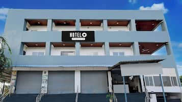 Um hotel com vários andares e um aviso indicando serviço corporativo. Possui diversas varandas e uma escadaria que leva à entrada.