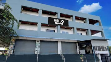 Um edifício de vários andares com uma placa indicando ser um hotel. Há persianas fechadas no andar térreo, sugerindo que o hotel está atualmente fechado.