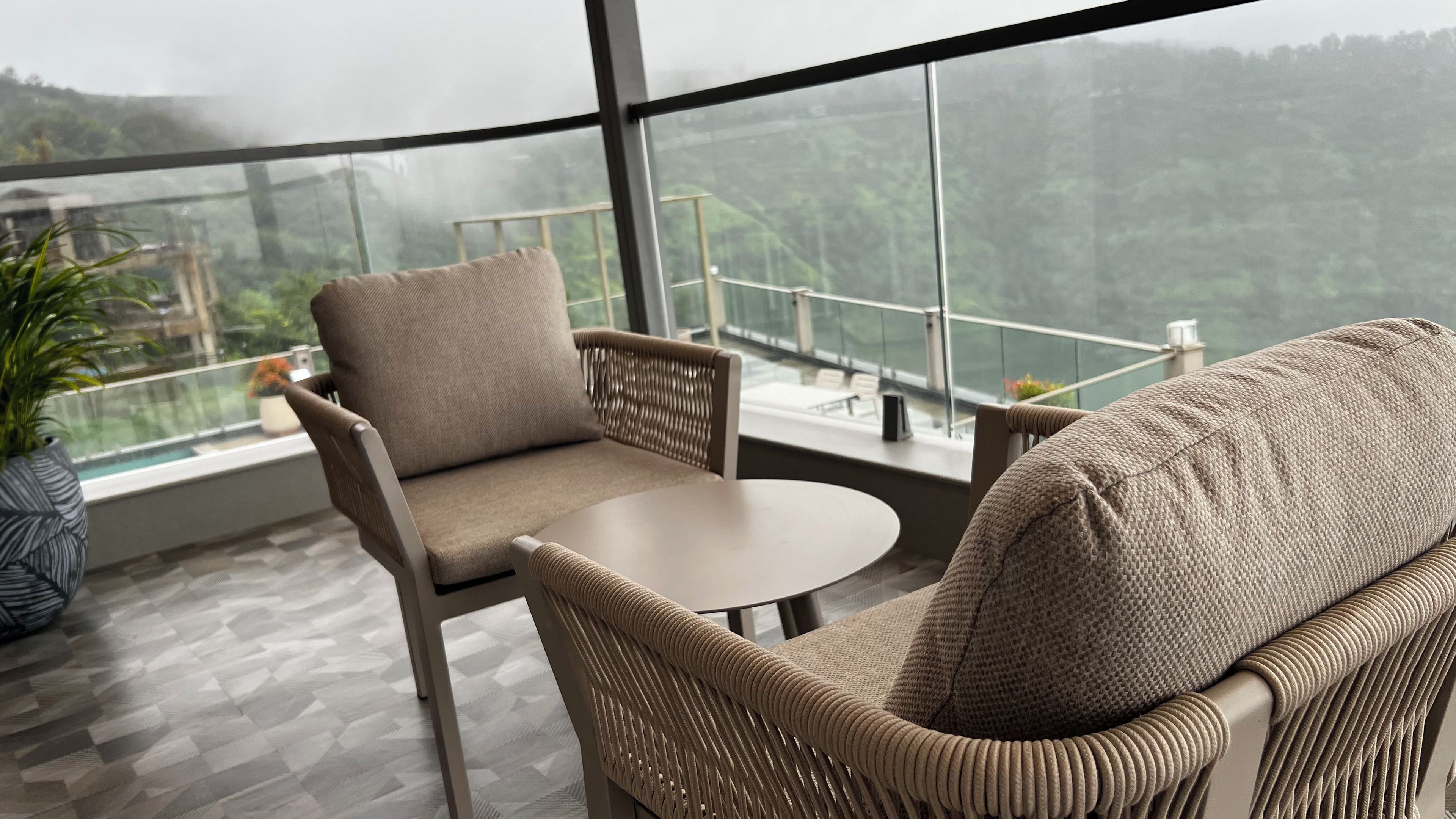 Varanda com móveis de vime, uma mesa redonda e vista para uma paisagem montanhosa.