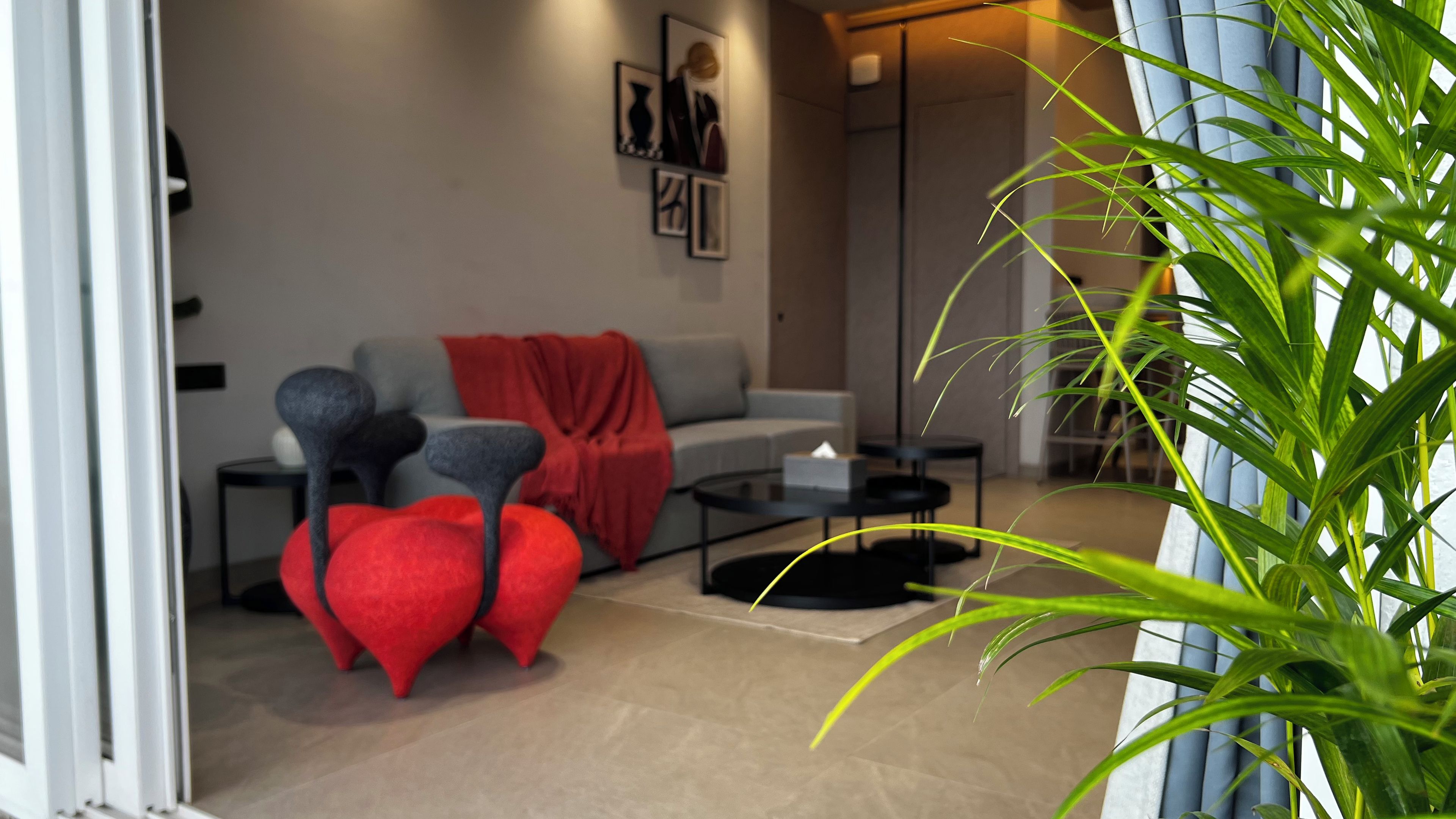 Sala de estar moderna com sofá, pufes vermelhos, mesa de centro e luminária de chão.