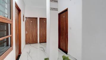Corredor com portas de madeira, placa indicando proibição de fumar e sinalização apontando para os quartos.
