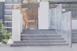 Escadas externas levam a uma entrada coberta com portão de metal.