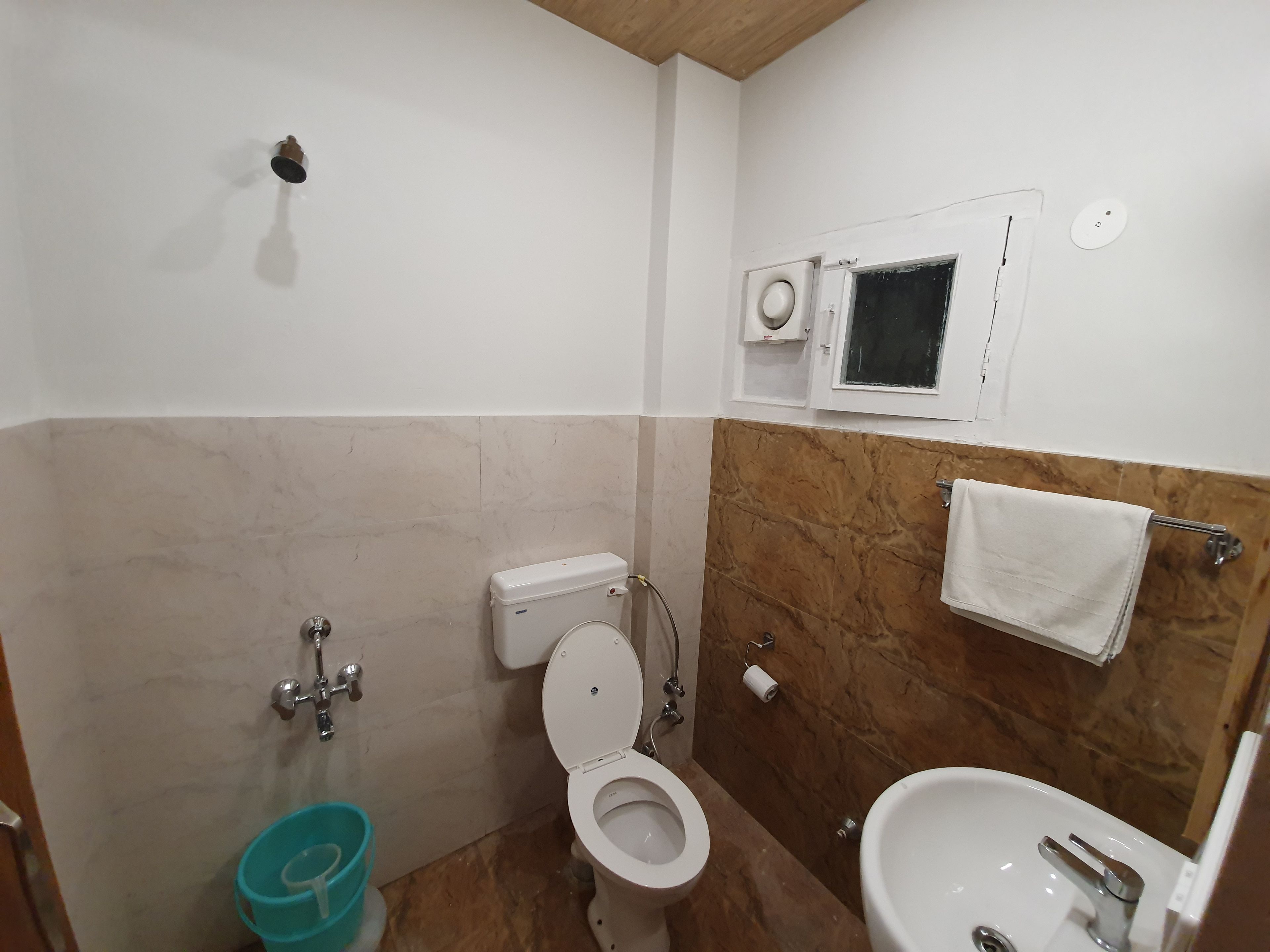 Casa de banho com sanita, lavatório e chuveiro.