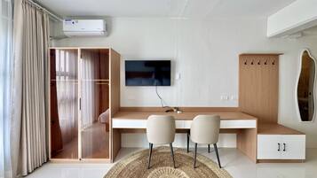 Quarto moderno com escrivaninha, duas cadeiras, televisão, guarda-roupa e espelho.