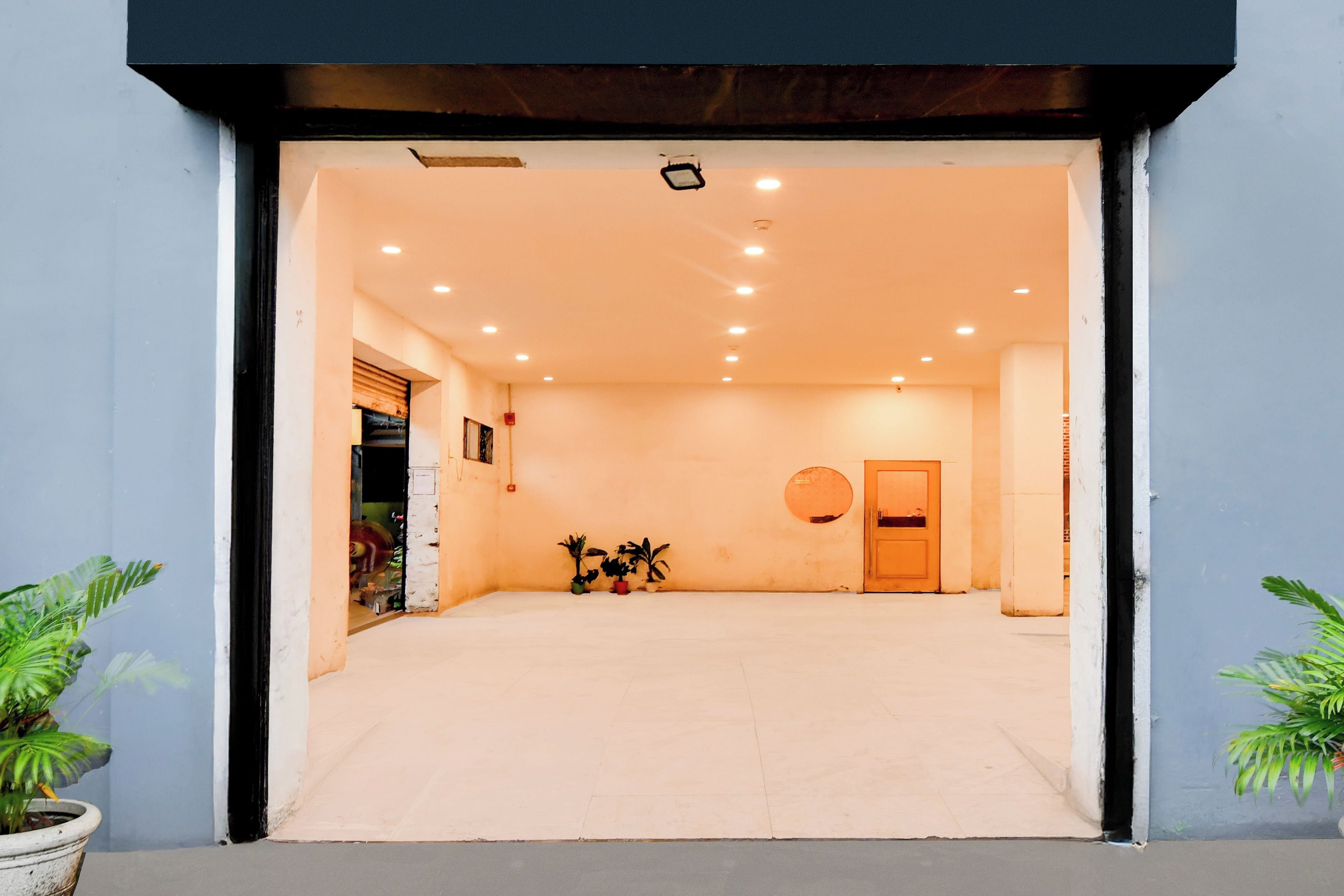Um espaço interior com piso de azulejos, uma porta e plantas em vasos.