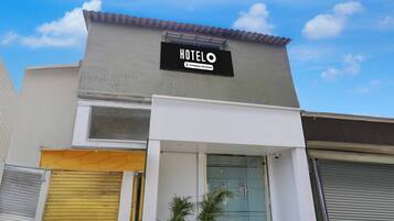 Um hotel chamado 'HOTEL' com placa da marca, fachada moderna e céu claro.