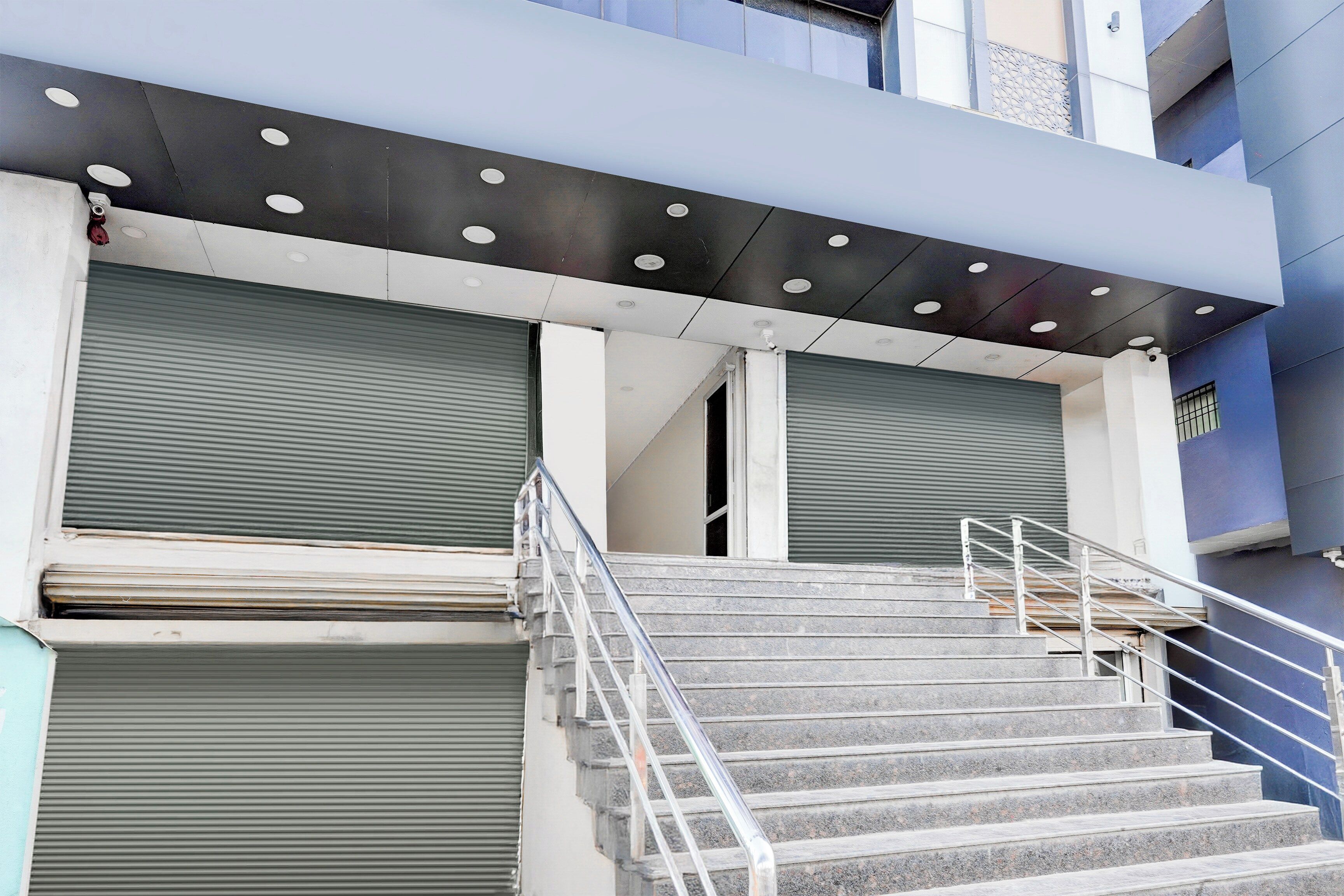 Escadaria que leva a um edifício com portões fechados, grades de metal e design moderno.
