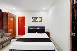 Quarto de hotel com cama, cadeira, guarda-roupa e porta.
