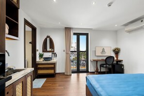 Quarto de hotel com cama, escrivaninha, cadeira e vista para a cidade pela janela.