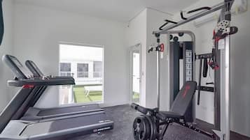 Academia com esteira, banco de musculação e diversos equipamentos de exercício.