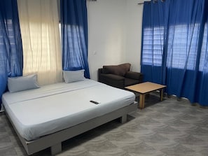Quarto com uma cama, uma mesinha e uma cadeira.